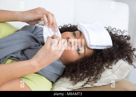 Woman with wet towel on her forehead suffering from headaches at home ...