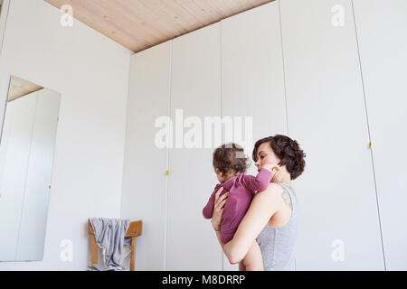 Low angle view, baby girl in pink dress looking up at the Christmas ...