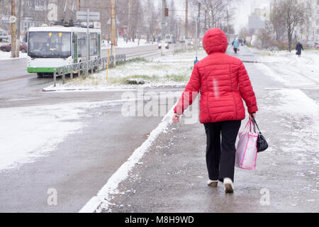 Woman wearing a red jacket throwing snow in the air in winter holidays ...