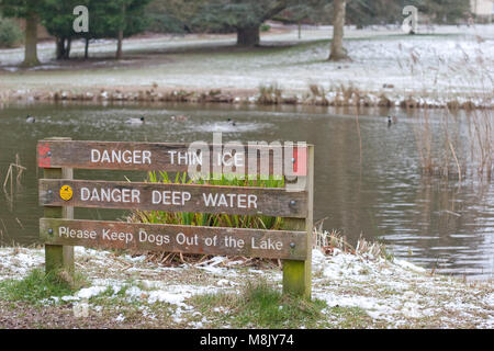 Pond warning signs in a park on a wooden post advising of deep water ...