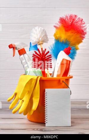 Plastic bucket with different cleaning supplies on white background ...