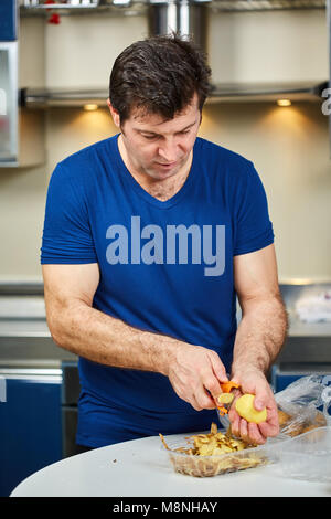 Man peeling potatoes on the counter in the kitchen Stock Photo - Alamy