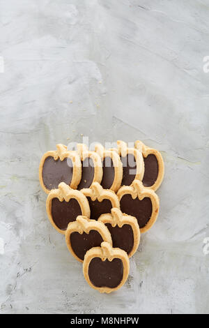 Sweet apple shaped cookies arranged in rows on light textured ...