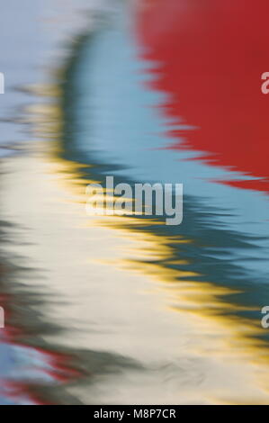 Shapes and colours in reflections of fishing boats in water of harbour ...