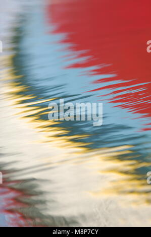 Shapes and colours in reflections of fishing boats in water of harbour ...