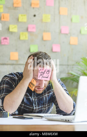 Stressed man with message on sticky notes over his face in office Stock ...