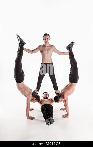 The group of gymnastic acrobatic caucasian men posing in balance ...