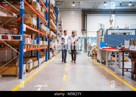 Two men walking in factory hall with rolls of rubber Stock Photo - Alamy