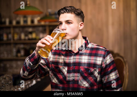 Man drinking beer. Side view of handsome young man drinking beer while ...