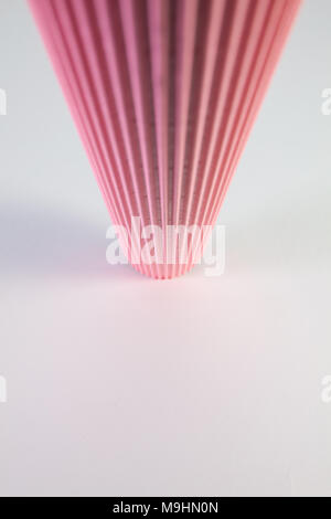 Corrugated pink paper roll on the white desk. Symmetry composition ...