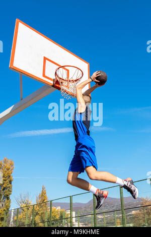 Young Basketball street player making slam dunk Stock Photo - Alamy