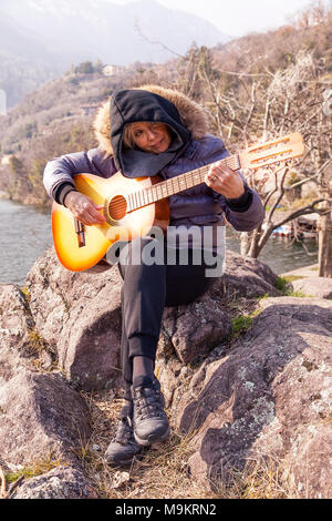 Portrait of smiling mature woman singing in kitchen with wooden spatula ...