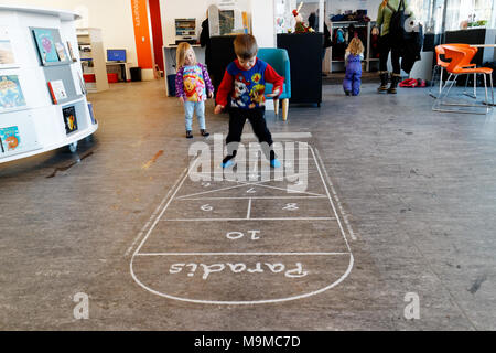 Playing hopscotch on an indoor hopscotch game in a public library in ...