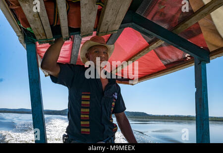 Mayan cowboy pilots a motor launch across a lake in northern Guatemala ...