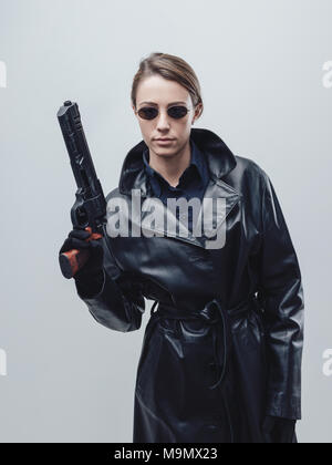 Cool female spy agent in black leather coat, she is holding a gun and ...