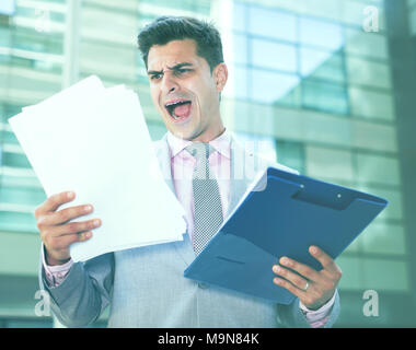 Confident businessman holding agreement papers absolutely dissatisfied ...
