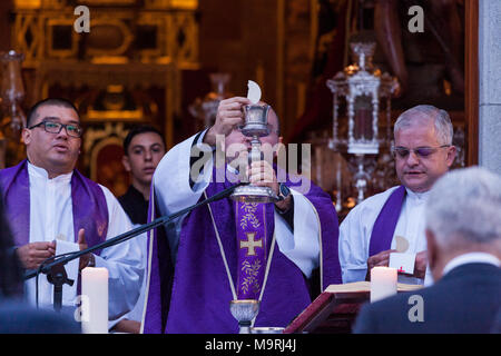 Priest holding host and wine chalice during holy communion while ...