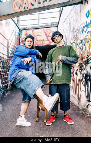 two rap singers with a dog in a subway with graffiti in the background ...