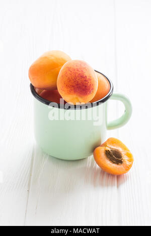 Apricot in tea cup on a white wooden table close up Stock Photo - Alamy