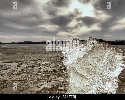 Icy sheets melting on sandy beach. End of long and crue winter coming ...
