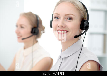 Image of bright call center. Focus on young blonde woman in a headset ...