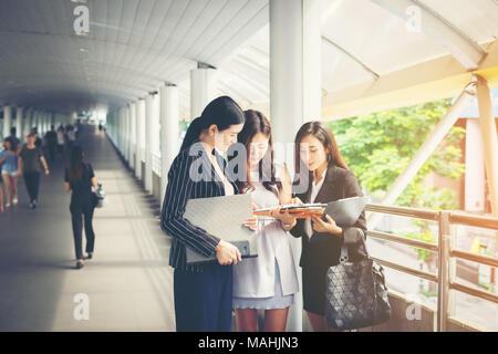 Businesswomen discussing over paperwork together against railing ...