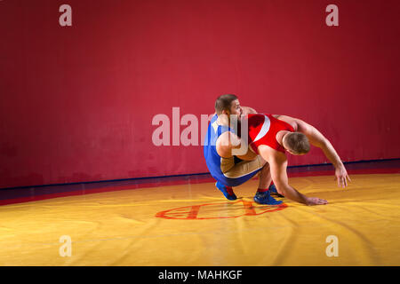Young athlete man, wrestlers in blue and red uniform hand wrestling in ...