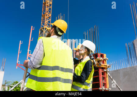 Young female builder and experienced foreman in hardhats and workwear ...