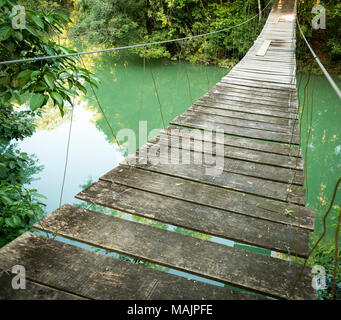 Epic wooden bridge hanging over jungle river as adventure travel scene ...