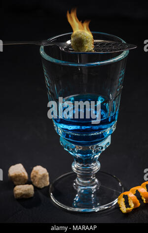 absinthe in glass with lemon slices on dark background with white sugar ...