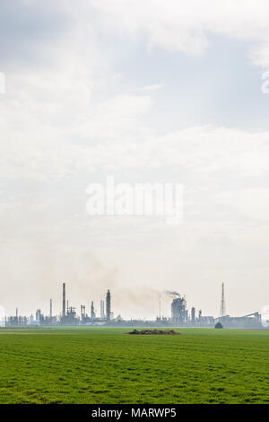 Oil refinery plant with smoking chimneys and gas flare on coastal cliff ...