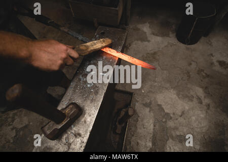 Blacksmith examining a hot metal rod Stock Photo - Alamy