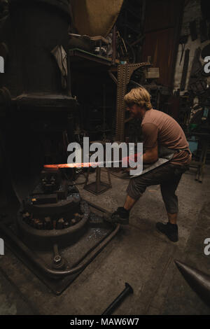 Blacksmith shaping hot metal rod in machine Stock Photo - Alamy