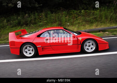Red modern classic Ferrari F40 in profile (side view) driving on the ...