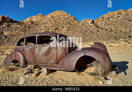 rusty old car, old-timer, with bullet holes on farm Klein-Aus, Namibia ...