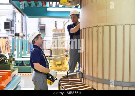 group worker assembles a transformer in mechanical engineering ...
