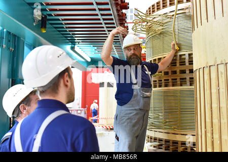 group worker assembles a transformer in mechanical engineering ...
