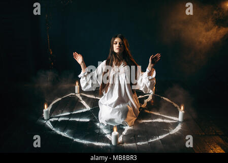 Witch in white shirt sitting in the center of pentagram circle with ...