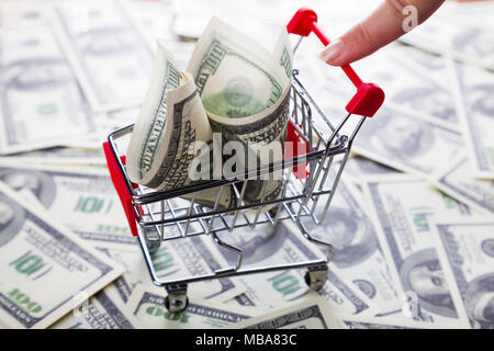 Shopping trolley with dollars and a woman's hand. Sale Stock Photo - Alamy