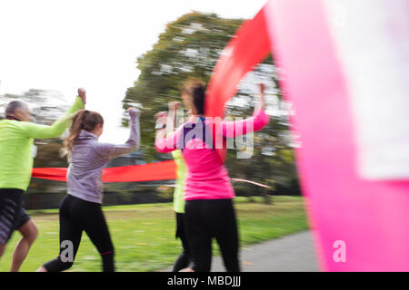 Enthusiastic family runners crossing charity run finish line in park ...