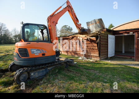 A large digger being used to demolish an old wooden barn Stock Photo ...