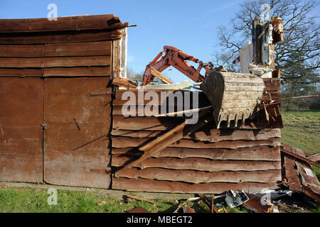 A large digger being used to demolish an old wooden barn Stock Photo ...