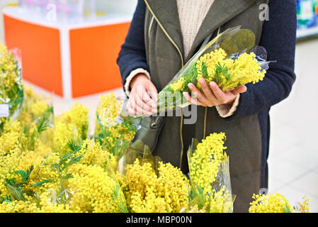 Girl buys flowers at a flower shop. She carefully selects best specimen ...