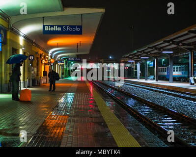 Two train drivers in station on a rainy night. Wet rails in the rain in ...