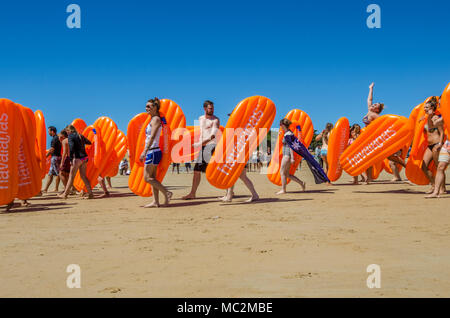 Beachgoers carrying inflatable Havianas flip-flops into the surf at ...