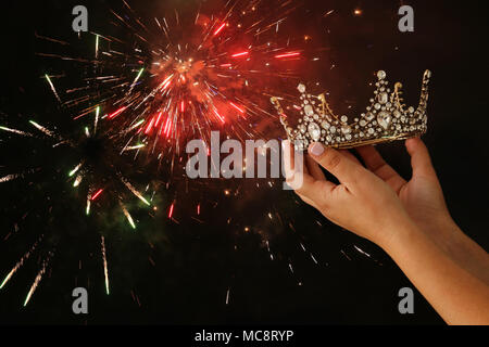 Woman's hand holding a crown for show victory or winning first place ...