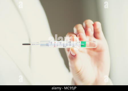 Doctor's hand holding classic traditional thermometer for measuring ...