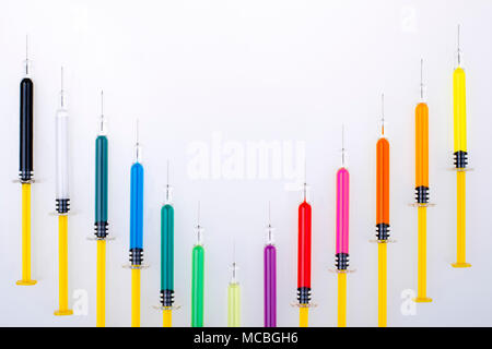 Multiple syringes with needles, filled with various colours of medicine ...