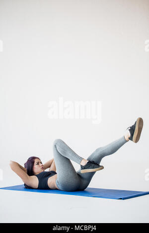 Toning her core. an attractive young woman working out in a studio with ...