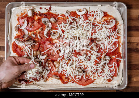 man spreading shredded cheddar cheese on to homemade pizza Stock Photo ...